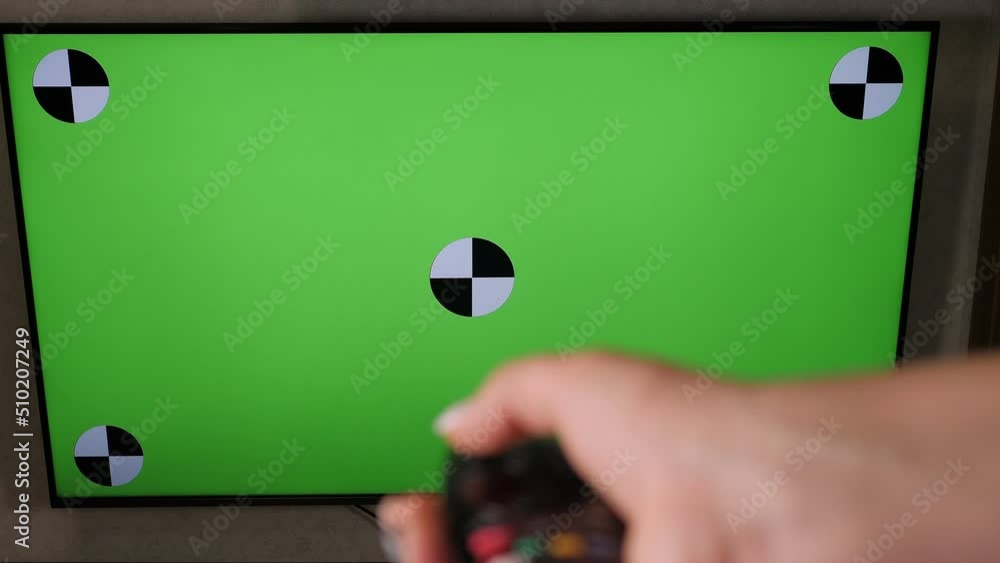 Hand holding TV remote controller over green screen a modern television ...