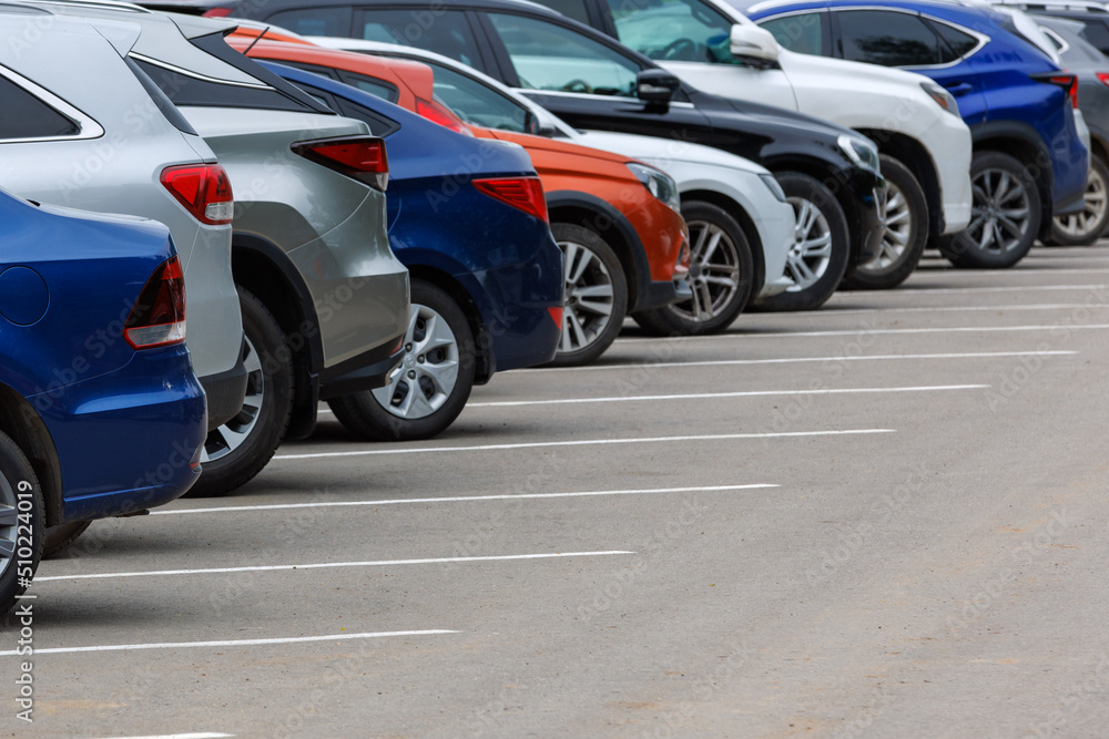row of different color cars on asphalt parking lot at cloudy summer day ...