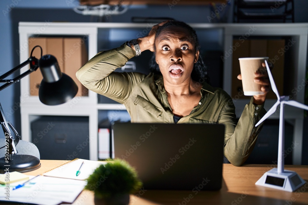 African woman working using computer laptop at night crazy and scared ...