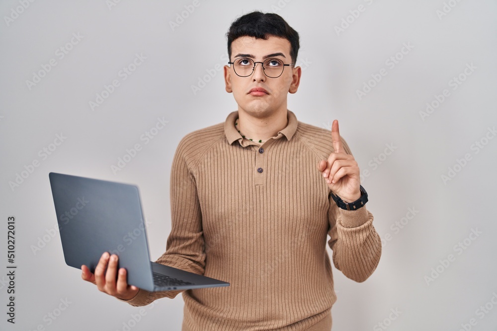 Non binary person using computer laptop pointing up looking sad and ...