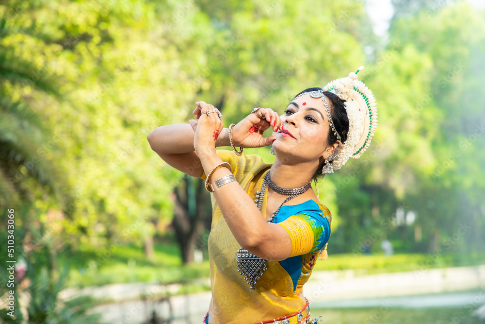 Indian woman Odissi dancer doing classical dance form outdoor at nature ...
