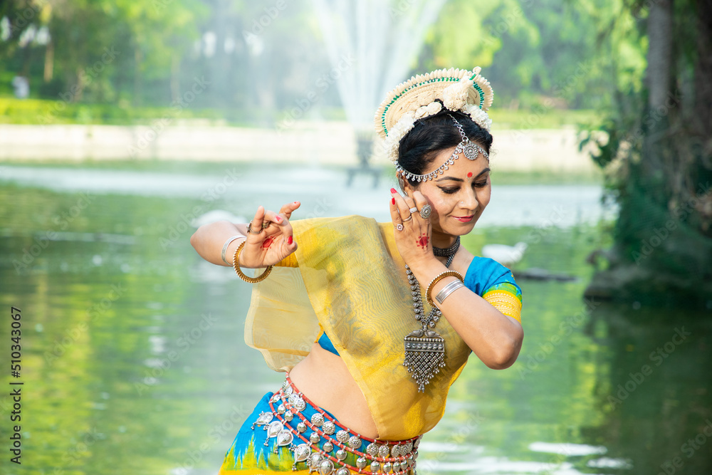 Indian woman Odissi dancer doing classical dance form outdoor at nature ...