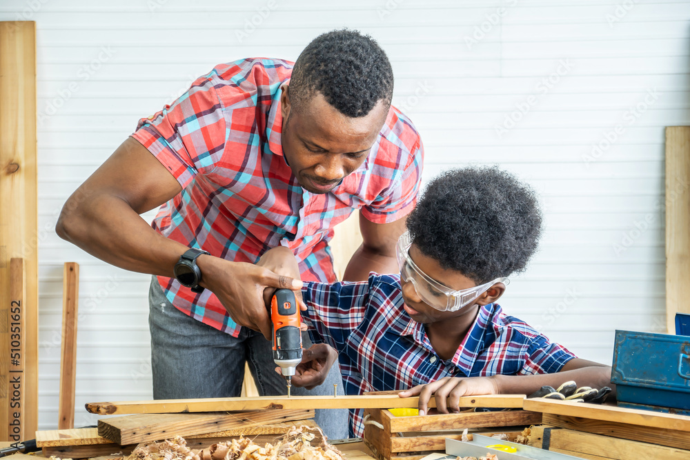 Careful father is teaching his son to work with electric screwdriver ...