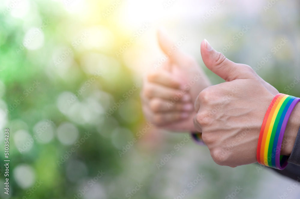 man wearing lgbt rainbow wristband hand thumb up symbol of cheer up or ...