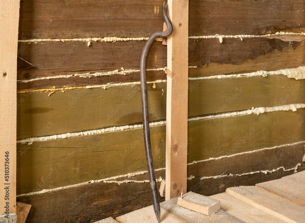 iron crowbar leaning against the log wall of the house, repair and ...