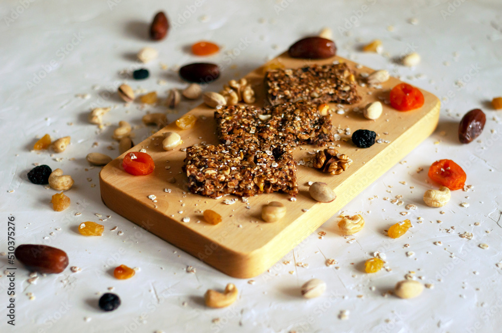bar with flakes, nuts and dried fruits on a light wooden board with ...