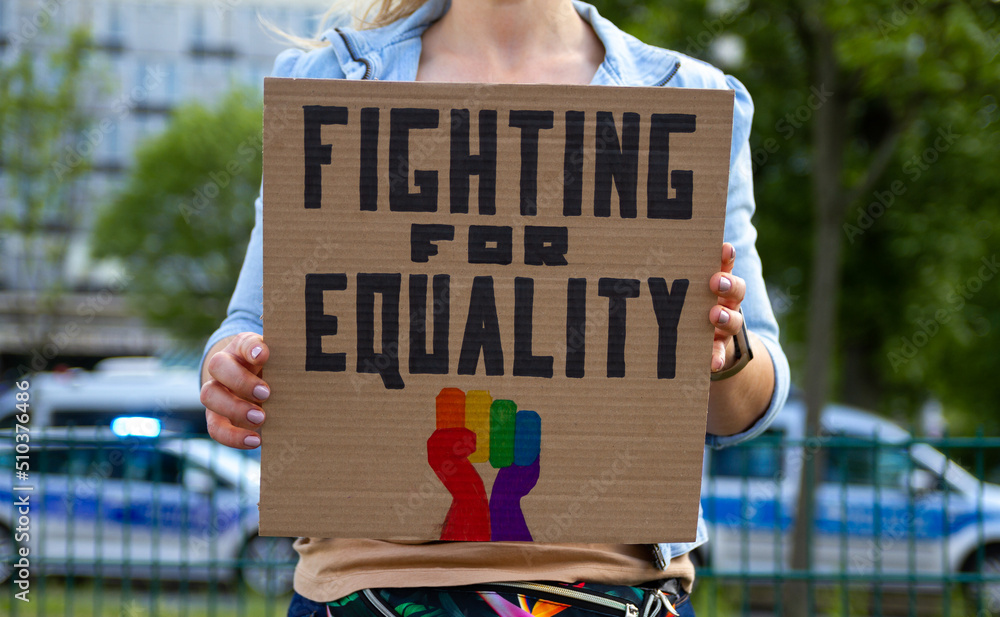 Woman holding placard sign Fighting for Equality with rainbow flag fist ...