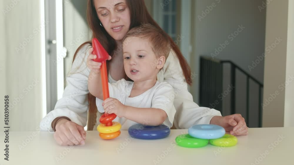 the child collects a toy pyramid. mom plays with son at home happy ...