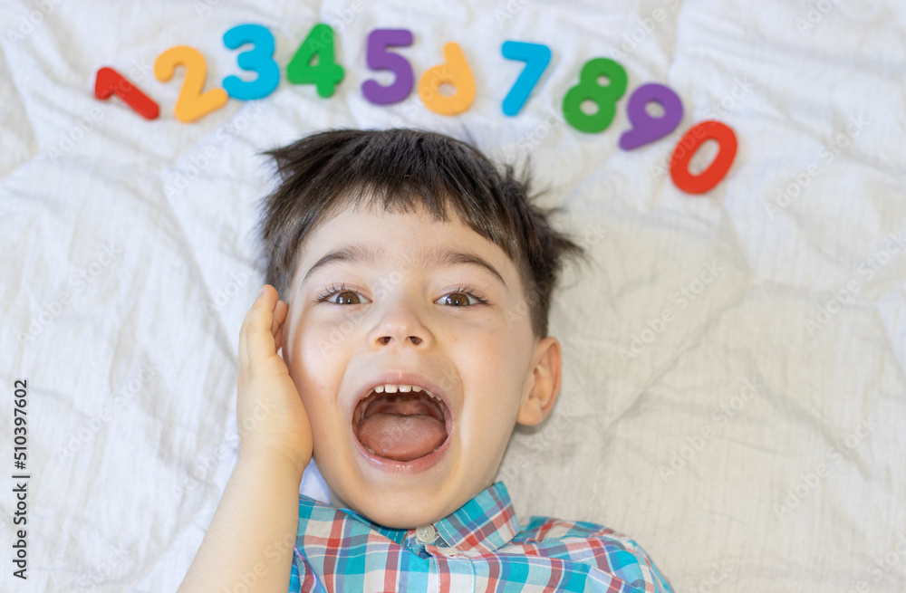 happy cheerful amazed kid with colorful wooden numbers above head.boy ...