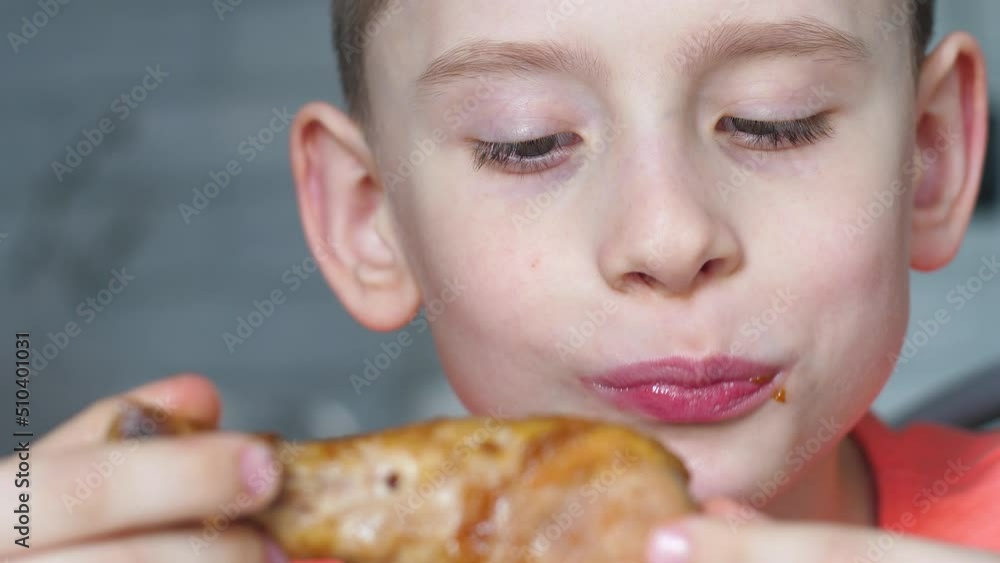 portrait of a caucasian boy 7 years old eating fried chicken legs with ...