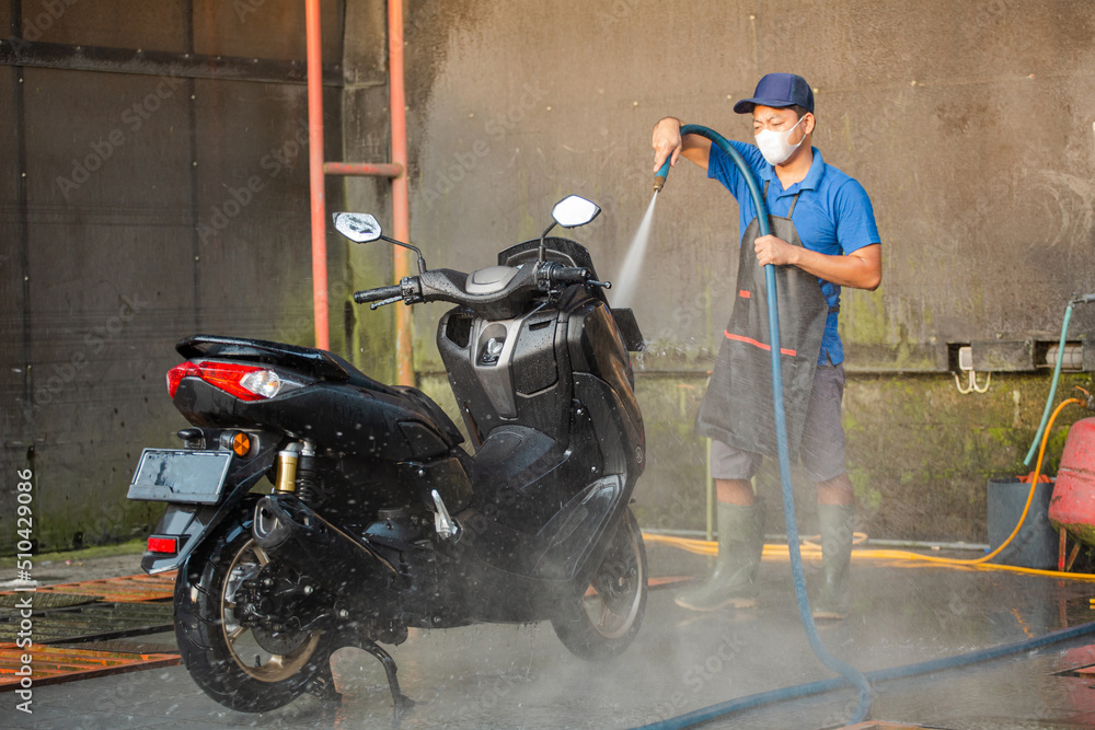 Worker using a hose for detailed cleaning. Spraying and washing a ...
