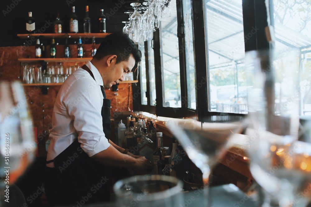 Handsome male bartender in apron preparing drink for customer at bar ...