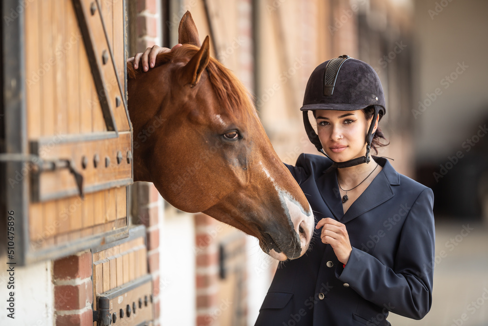 Female jockey in helmet and riding uniform gets ready for horse races ...