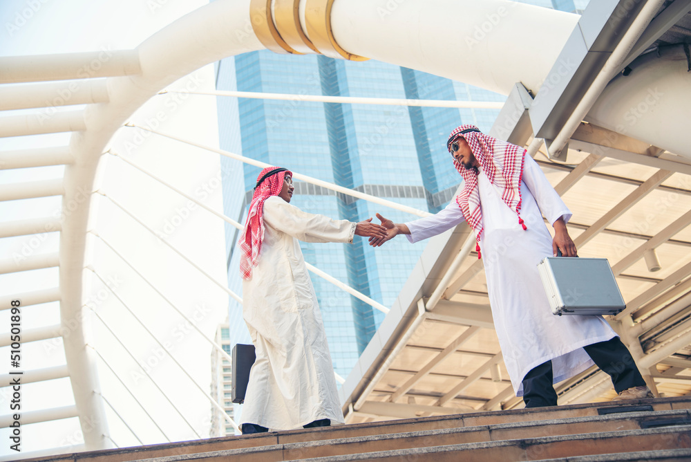 Arab Businessman Muslim dress shaking hands together in modern city UAE ...