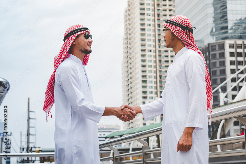Arab Businessman Muslim dress shaking hands together in modern city UAE ...