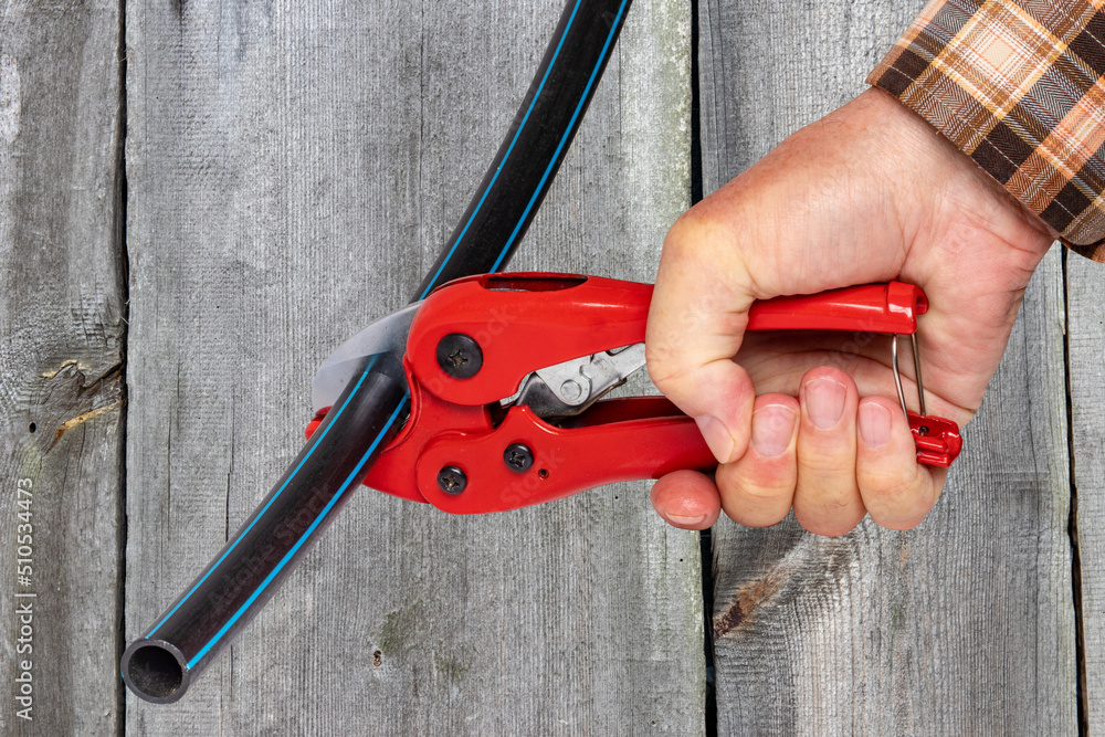 Craftsman tools. A man accurately cuts a piece of PE pressure pipe or ...