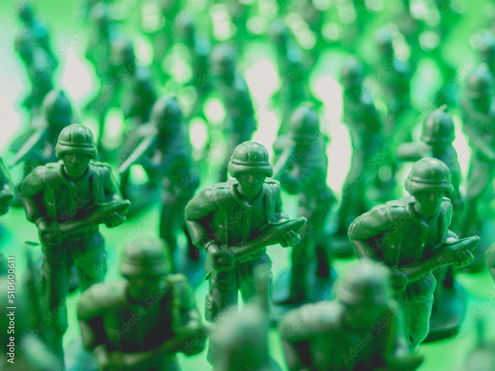 Small toy soldiers of green color in battle in front of green ...