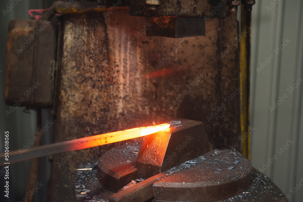 Professional male blacksmith forming red hot metal on an anvil in ...