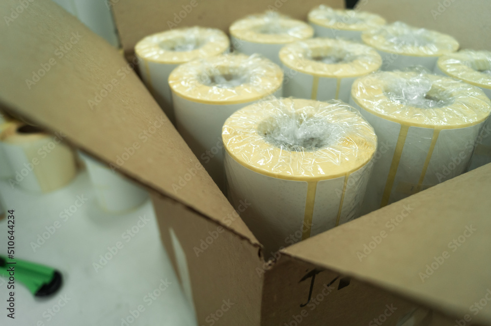 Packed in a cardboard box rollers of white self-adhesive labels for ...