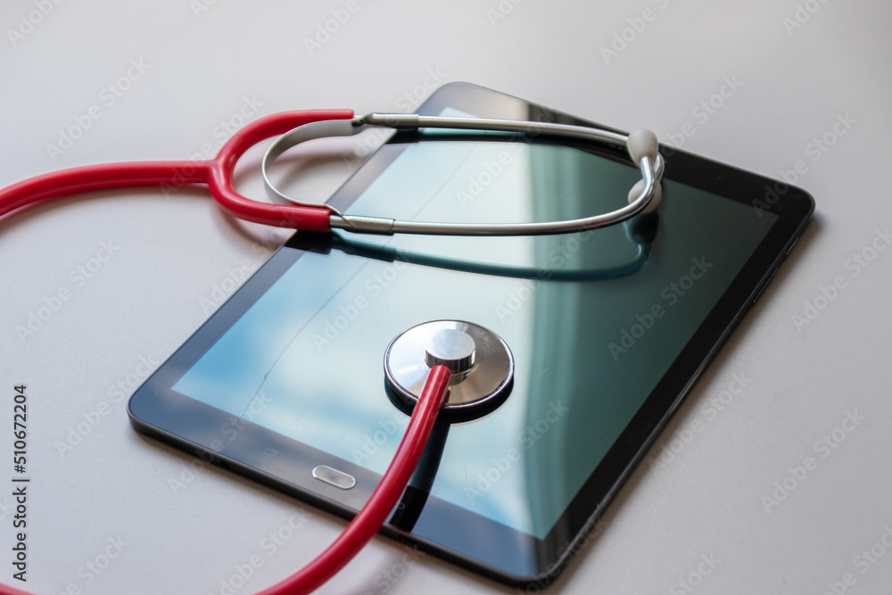 Red stethoscope on black tablet device shows health records and digital ...