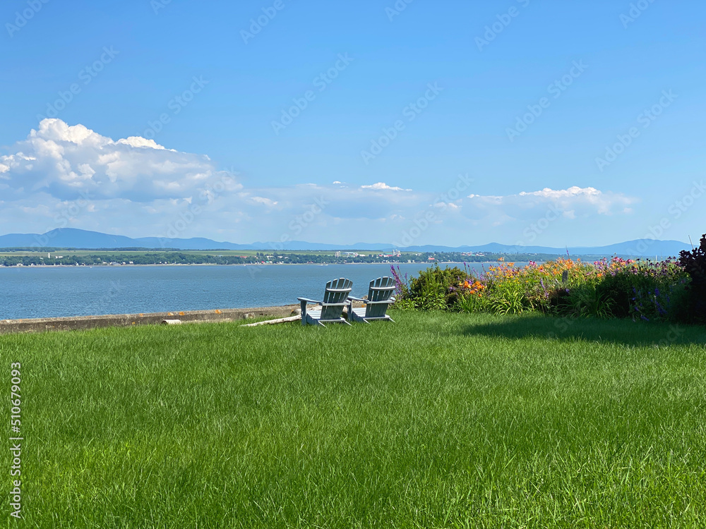 Chaises adirondack sur le bord du fleuve. Terrain gazonné pour se ...