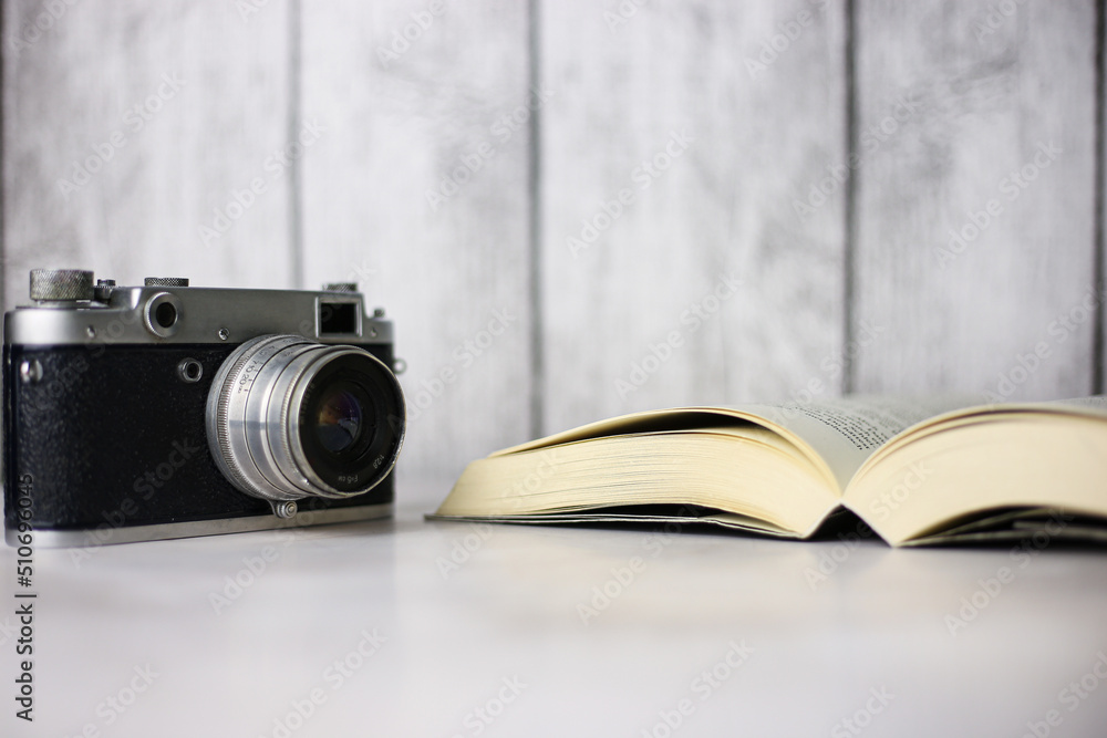 Vintage camera next to an open book on a light background Stock Photo ...