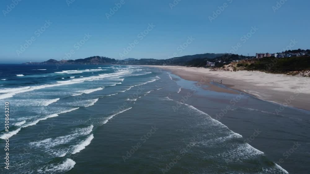 Zoom-in drone shot flying over waves at Nye Beach on the Oregon coast ...