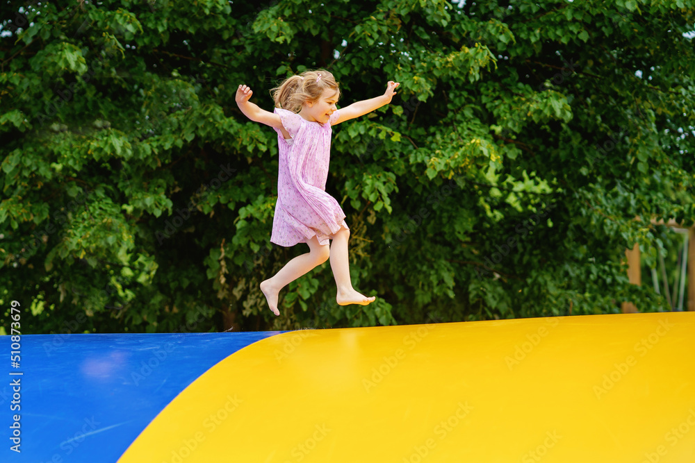 Little preschool girl jumping on trampoline. Happy funny toddler child ...