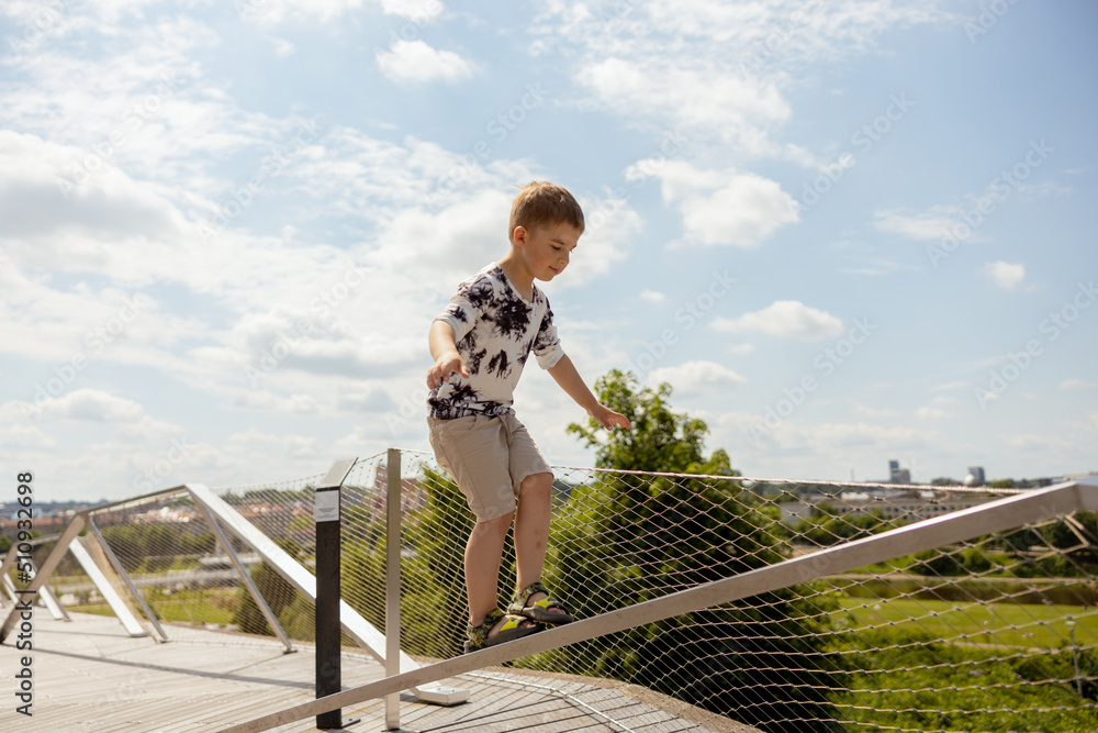 Adorable caucasian boy climbing on metal handrail outdoor. Cute child ...