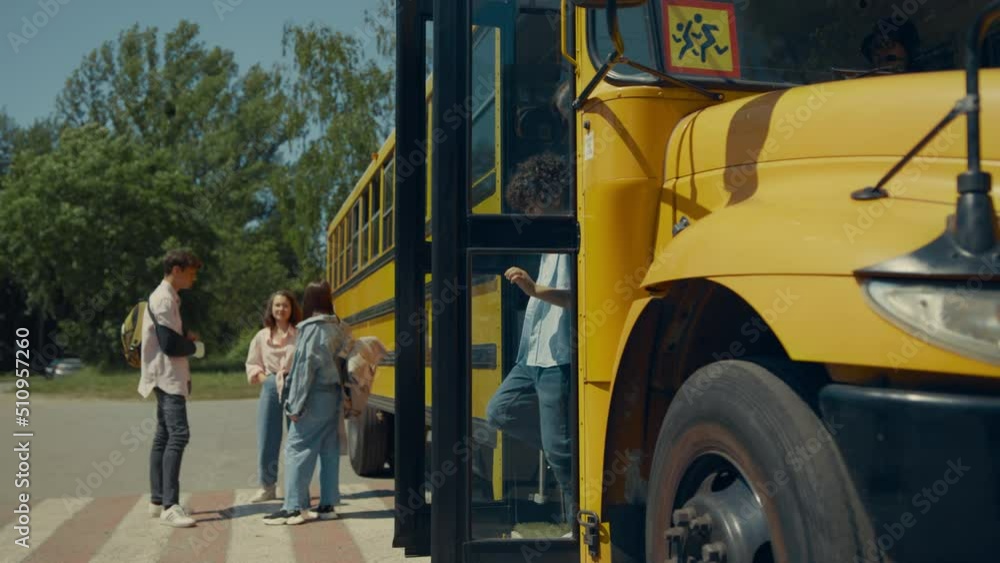 Two school children going out schoolbus. Teenagers standing at bus ...