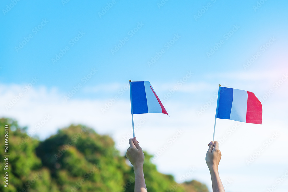 hand holding France flag on blue sky background. holiday of French ...