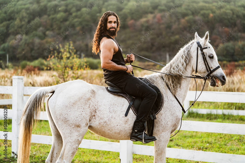 Hunky cowboy. Young muscular guy in t-shirt on horseback. Man riding a ...
