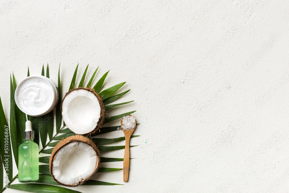 Coconut with jars of coconut oil and cosmetic cream on colored ...