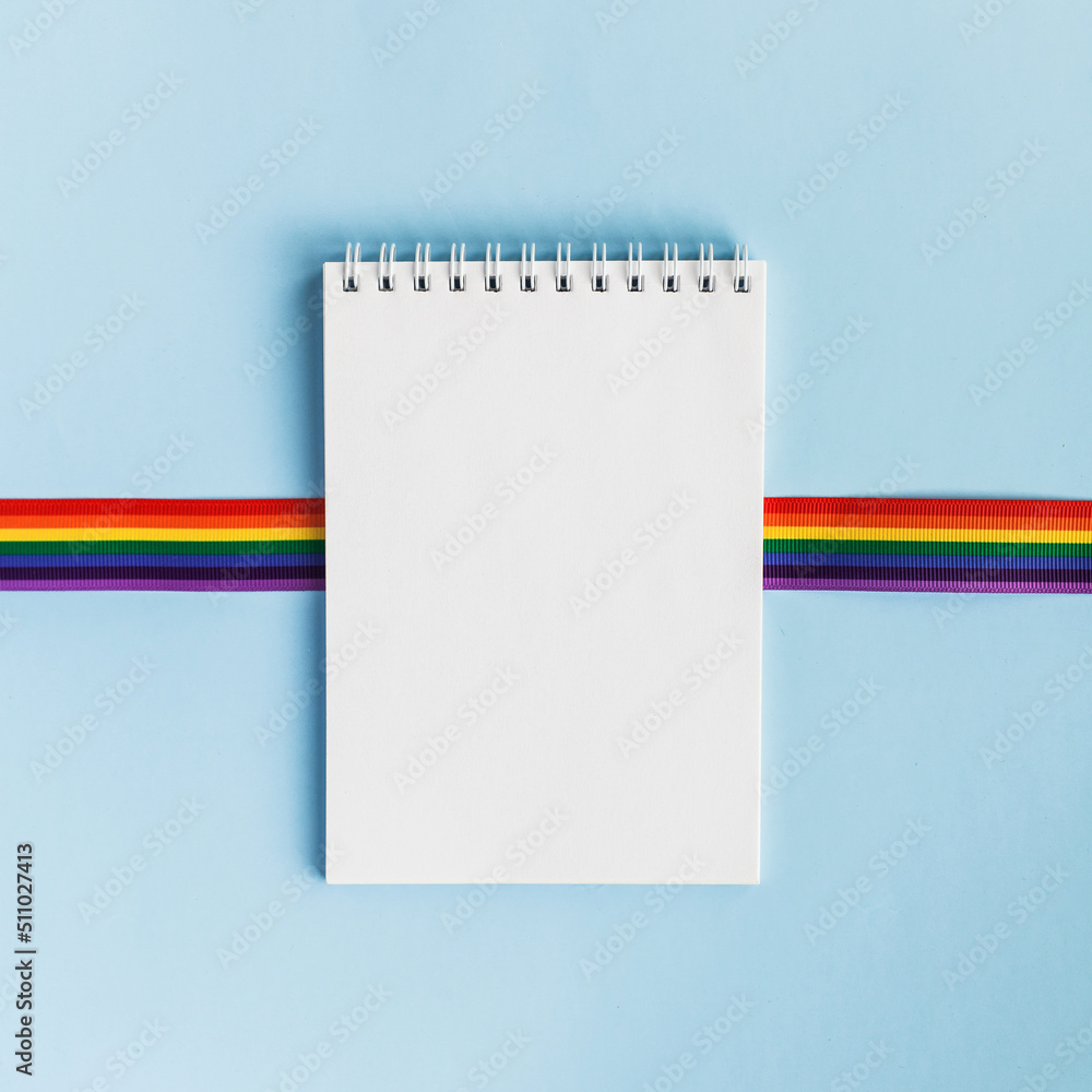 LGBT raibow flag ribbon with notebook or note mock up on light blue ...