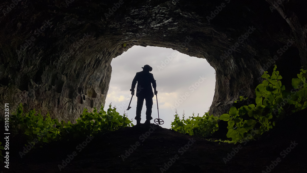 treasure hunter with metal detector searching inside the cave in the ...