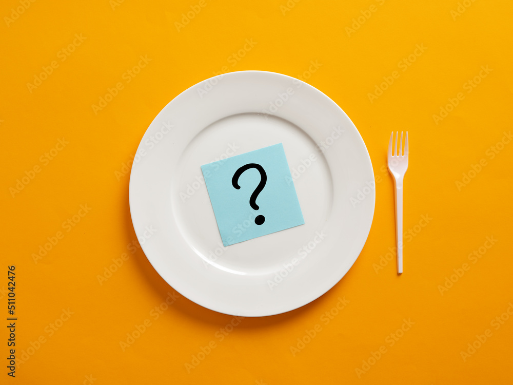 Notepaper with question mark symbol on a white plate with yellow ...