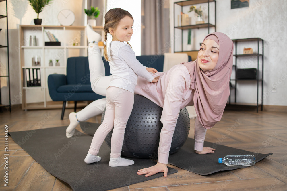 Smiling positive young muslim woman doing morning sports exercises at ...