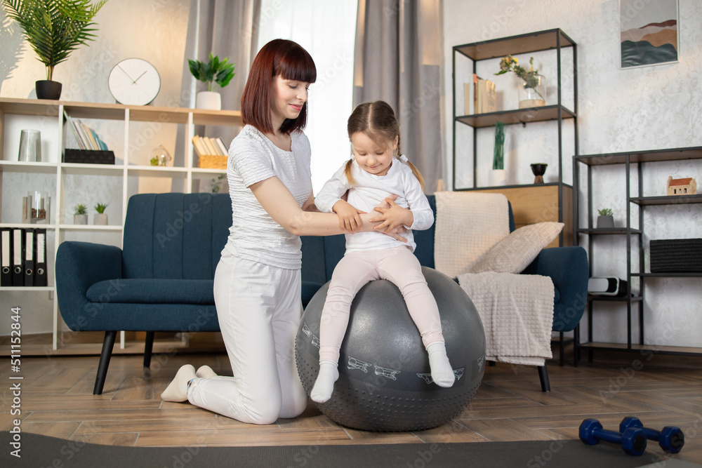 Happy fitness family training on swiss ball in living room. Portrait of ...