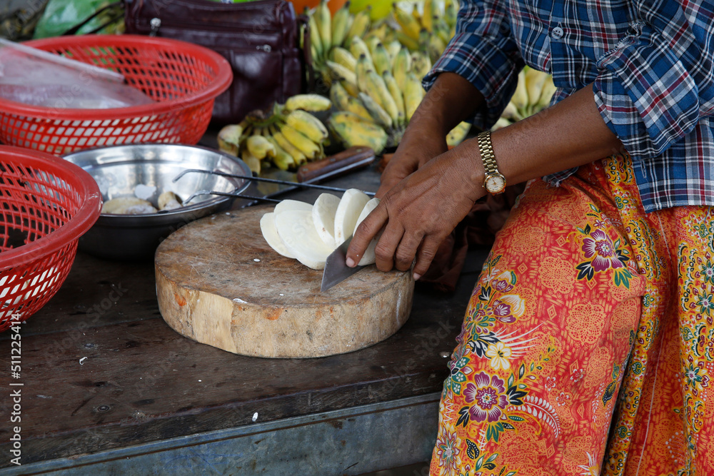 Cambodian muslim woman making and selling banana fritters, peanuts and ...