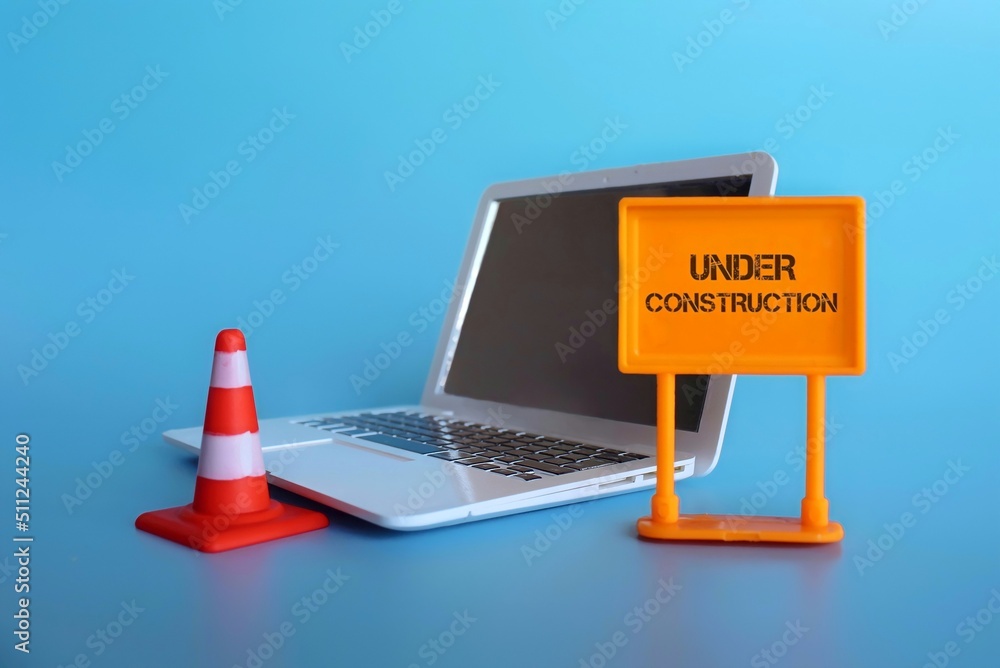 Foto de Website under construction concept. Laptop, safety cone and ...