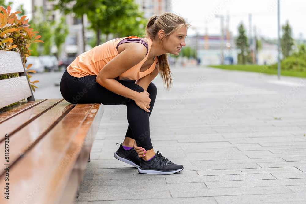 Young woman with aching leg. Sportswoman with injured ankle. Runner ...