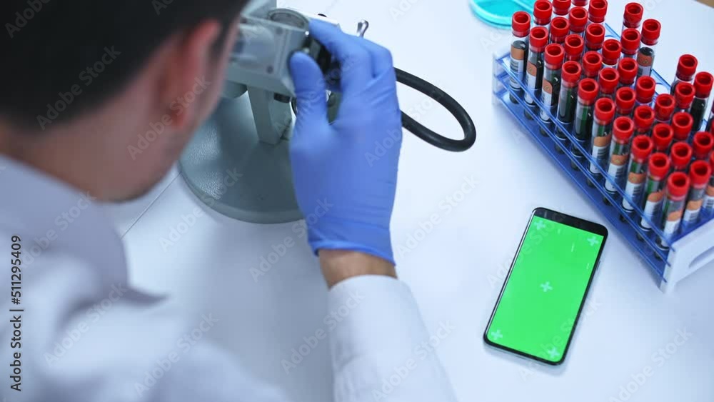DNA heritage lab worker studying blood under microscope, green screen ...