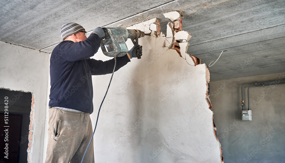 Man builder drilling wall with electric hammer drill. Male worker using ...