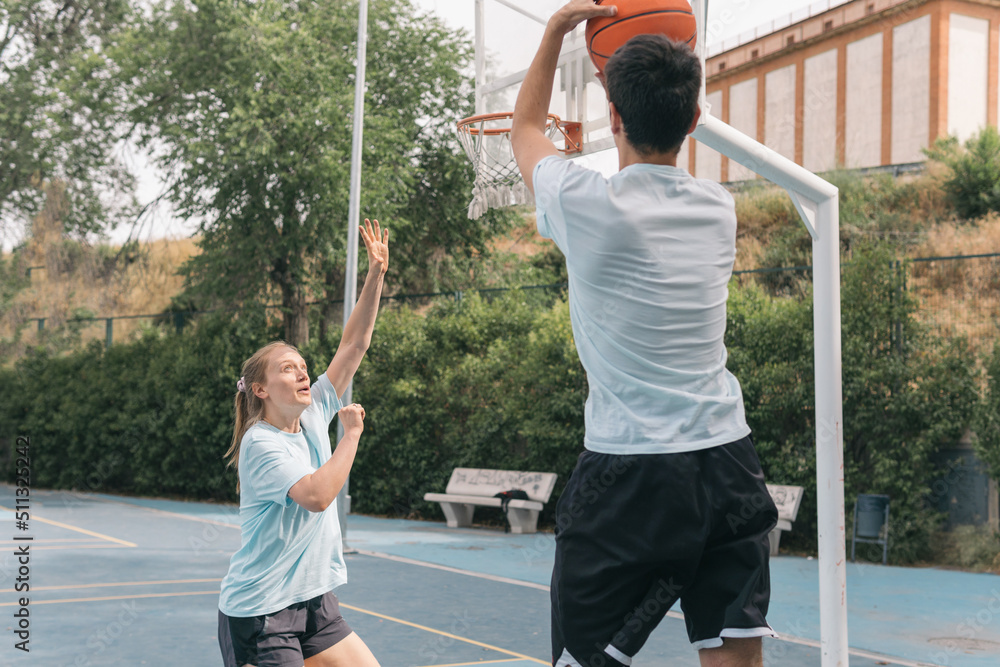 Dark-haired boy shooting a triple shot on the basketball court while ...