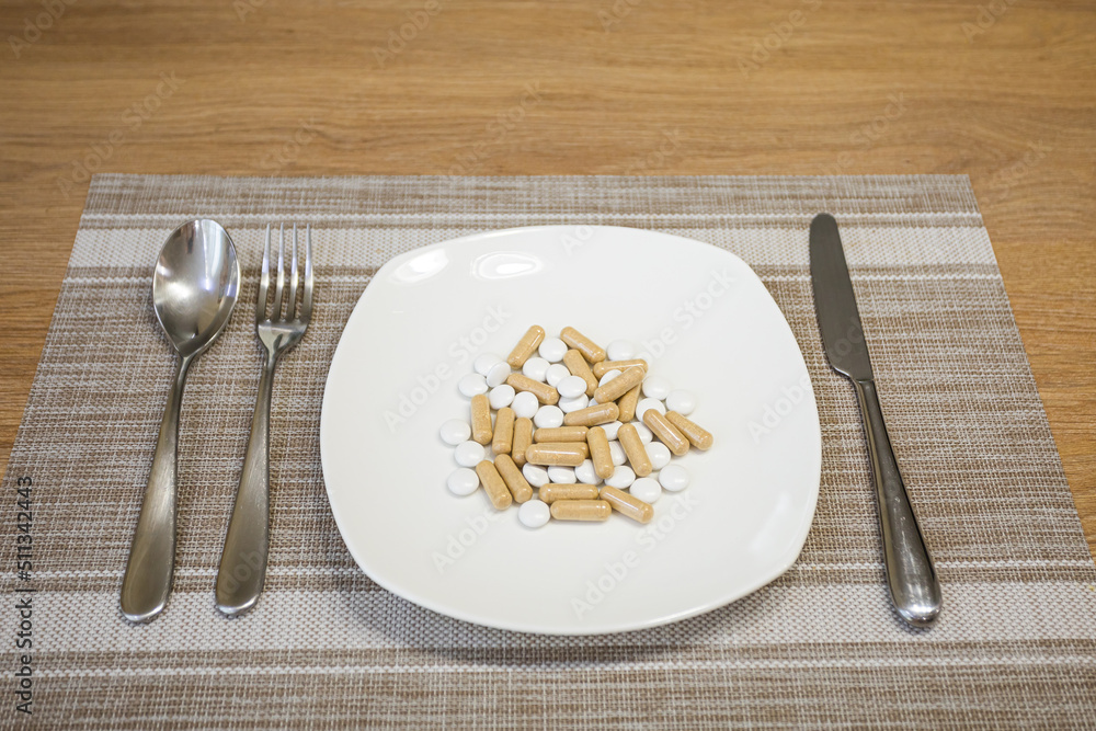 A plate of pills of medicine vitamins instead of lunch with cutlery ...