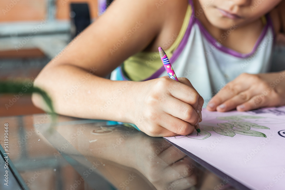 latina girl with brown skin, coloring her drawing of green leaves on a ...