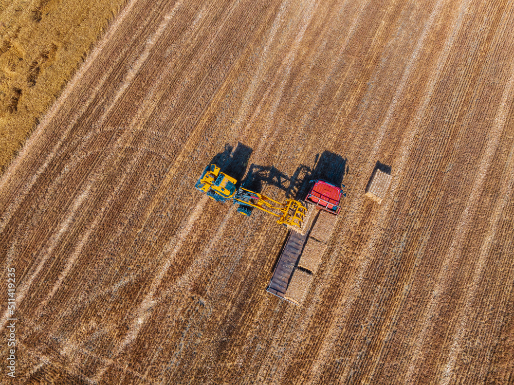 Agricultural tractor loads wheat straw on truck. Aerial view ...