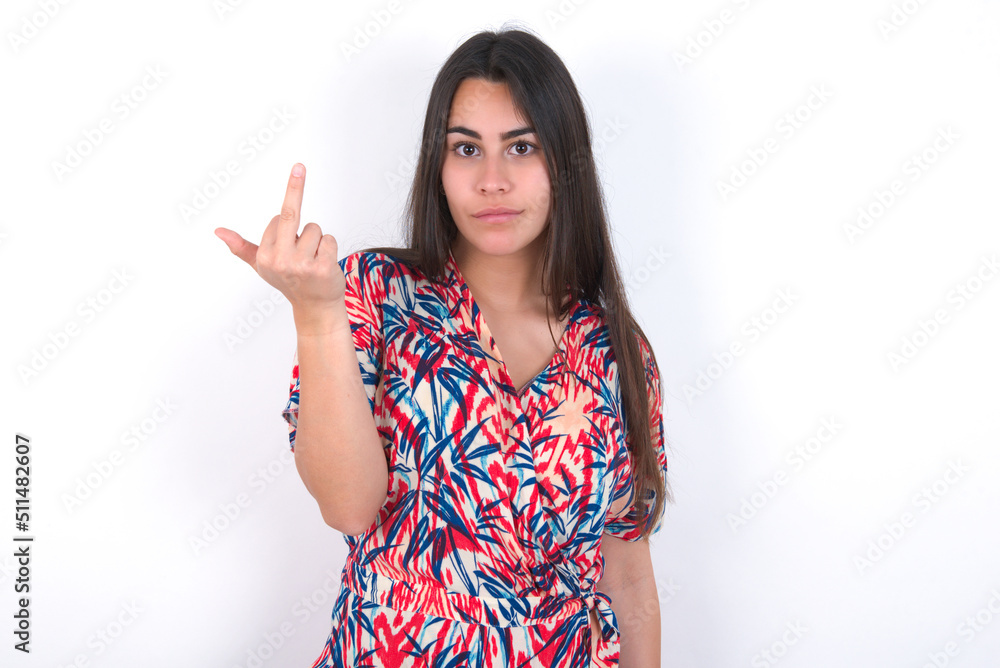 young beautiful brunette woman wearing colourful dress over white wall ...