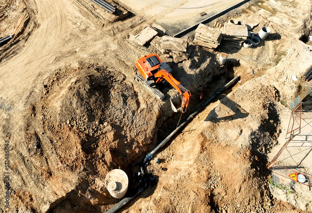 Sewage drainage system mounting at construction site. Excavator during ...