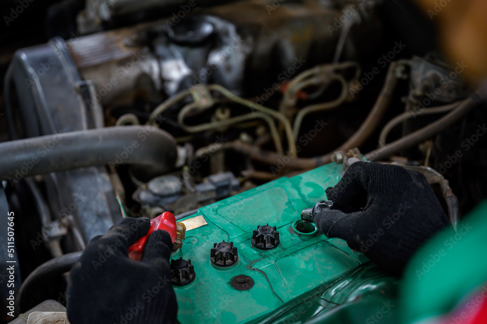 mechanic checks the car battery distilled water level and fills the ...